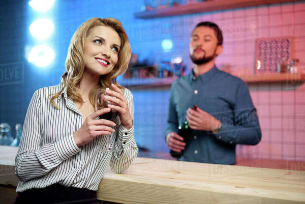 Young smiling blonde woman holding glass of wine and flirting with ...