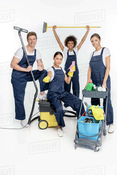 group of smiling multiethnic cleaners with equipment looking at camera ...