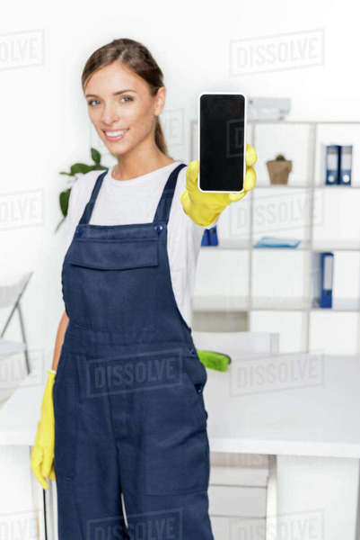 beautiful young female housekeeper holding smartphone with blank screen ...