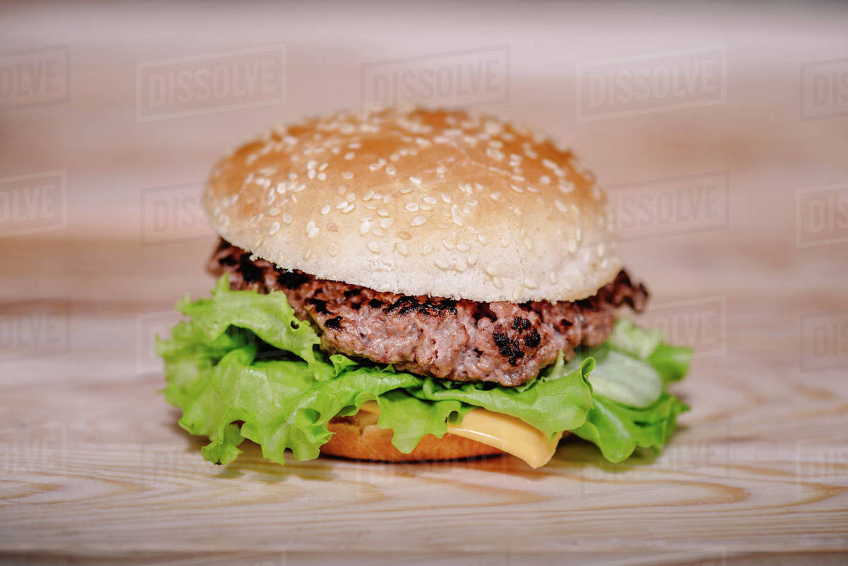 Close up view of freshly cooked meat burger on wooden tabletop ...