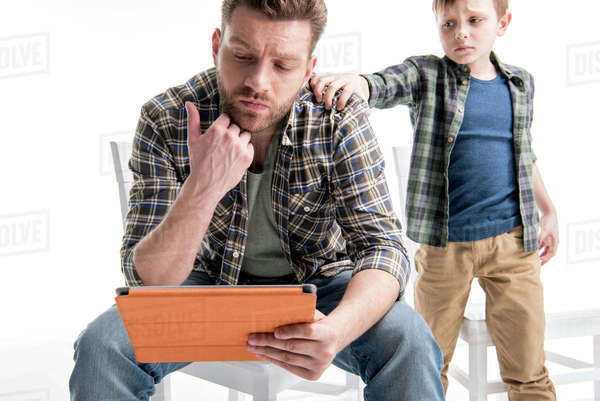 Upset little boy trying to talk with father using digital tablet ...