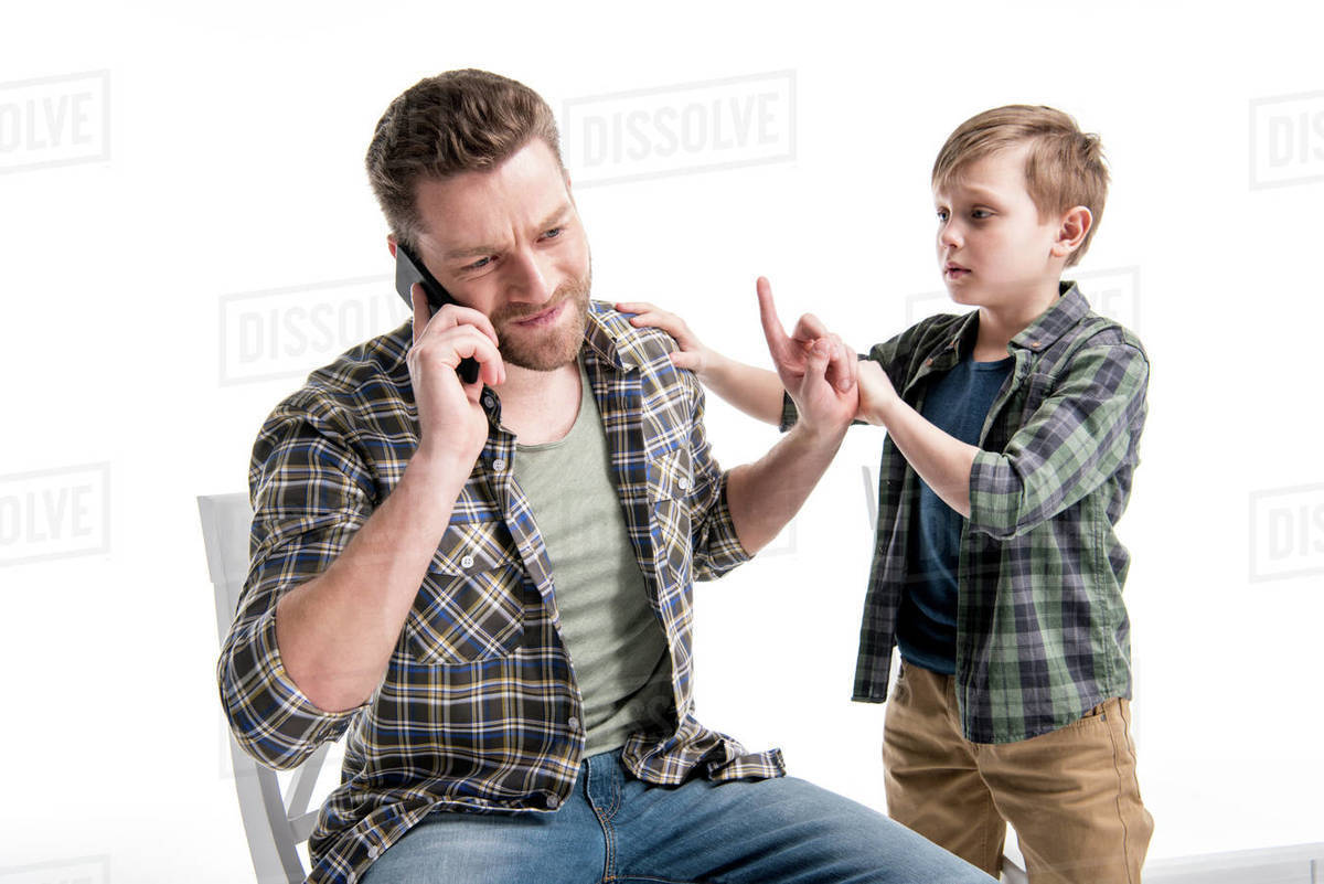 Little boy trying to talk with father talking on smartphone and ...