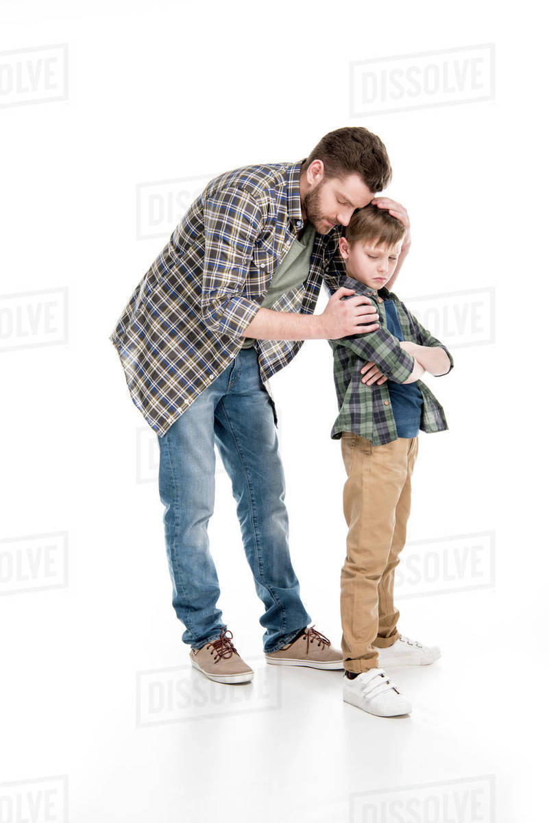Father embracing serious son standing with crossed arms, family ...