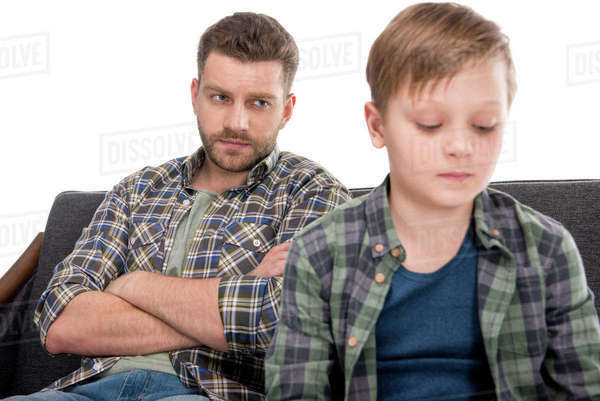 Serious father with crossed arms looking at upset little boy, family ...