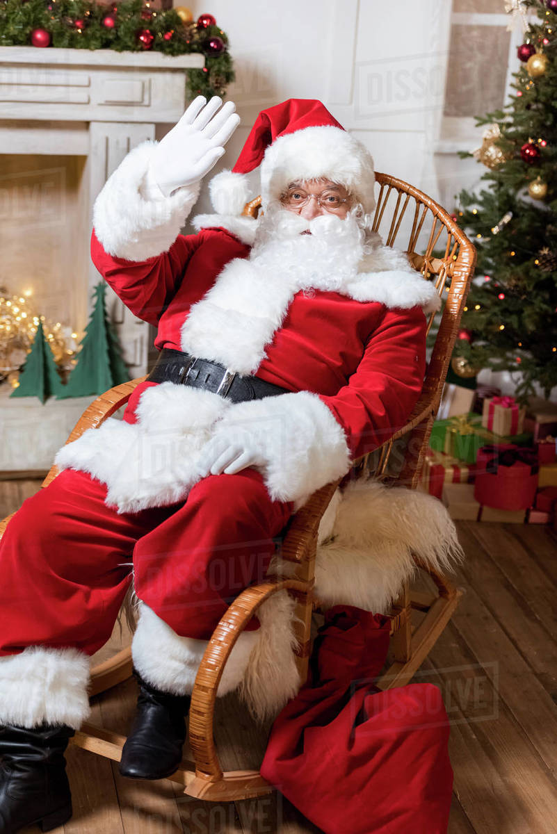 Santa Claus waving at camera while sitting in rolling chair - Royalty ...