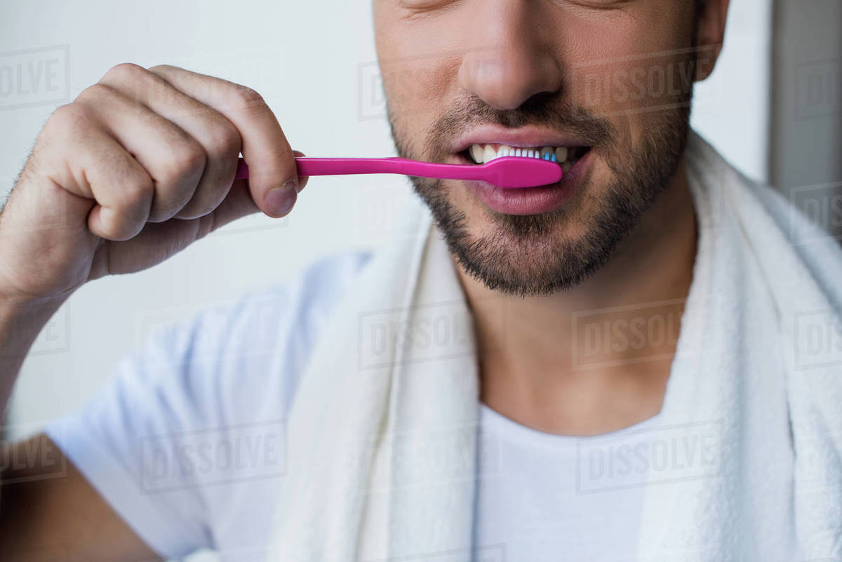 Cropped shot of young man brushing teeth with pink toothbrush - Stock ...