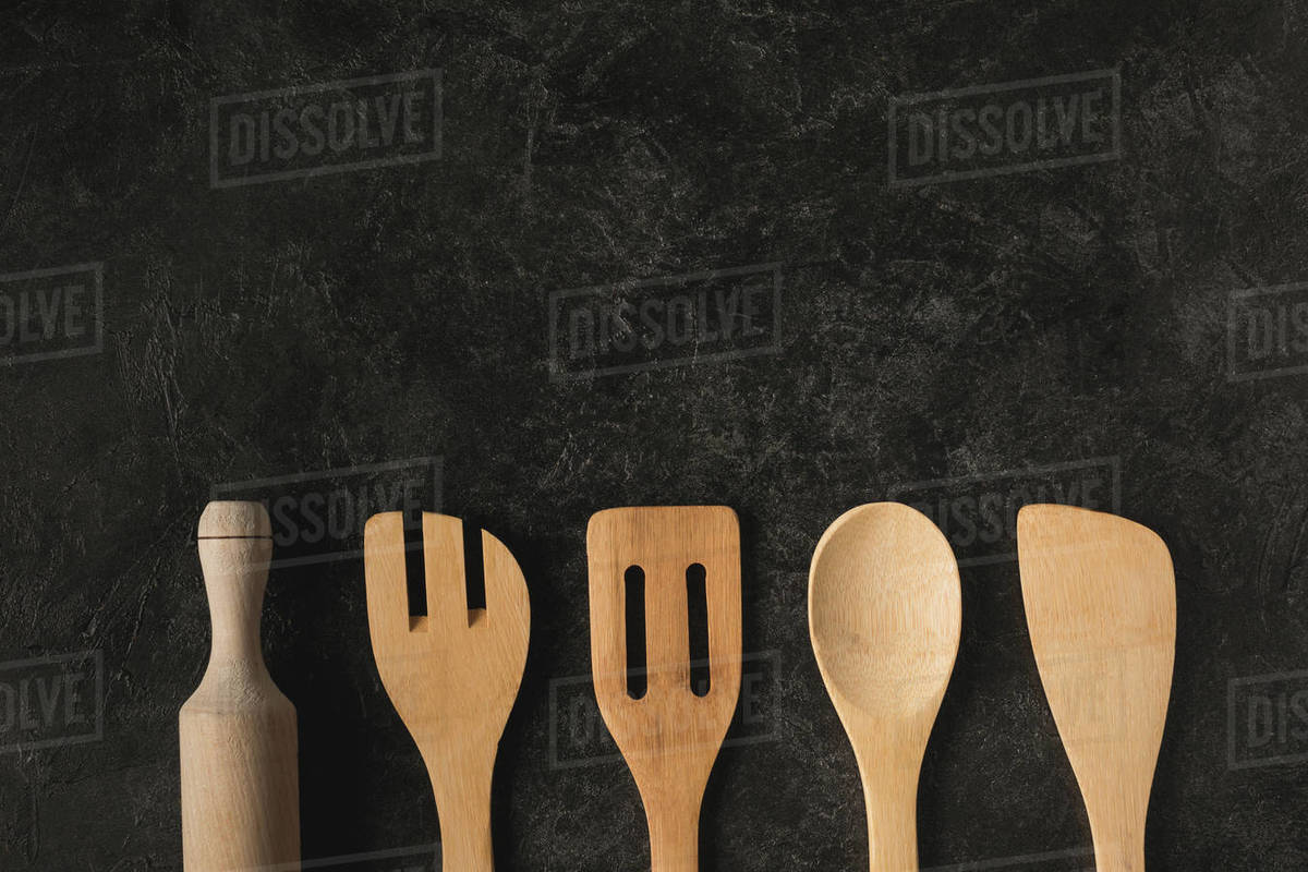 Flat lay with arranged wooden kitchen utensils isolated on black ...