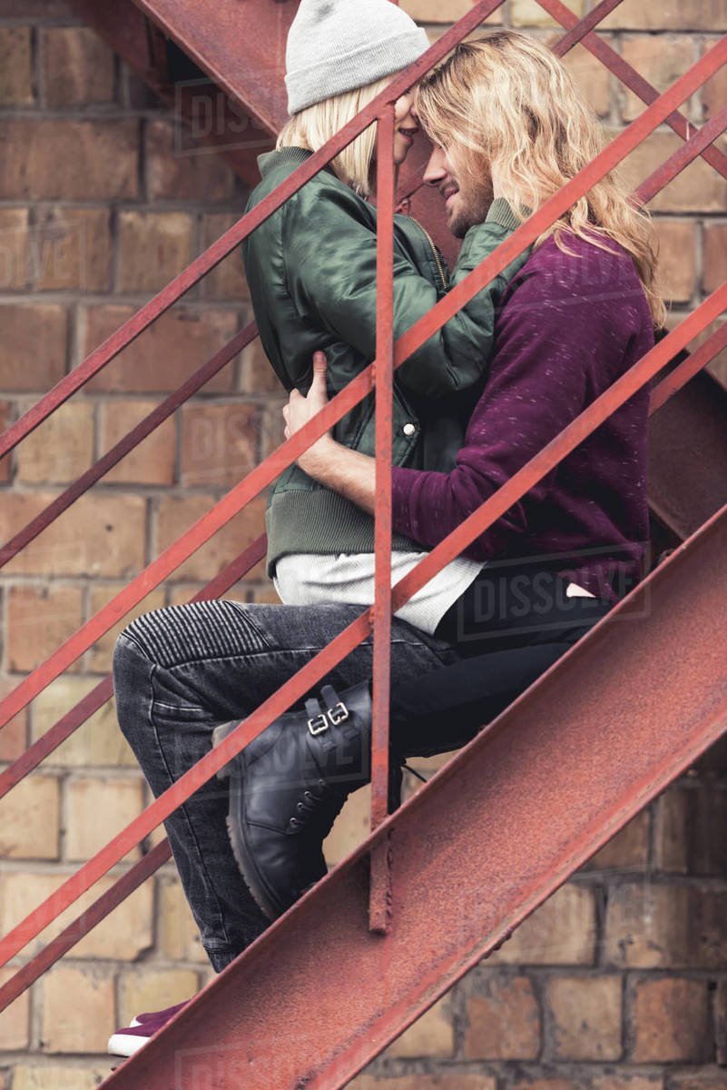 Beautiful stylish couple sitting on stairs and embracing - Stock Photo ...