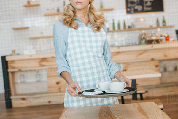 cropped shot of waitress holding tray with cups and saucers - Royalty ...