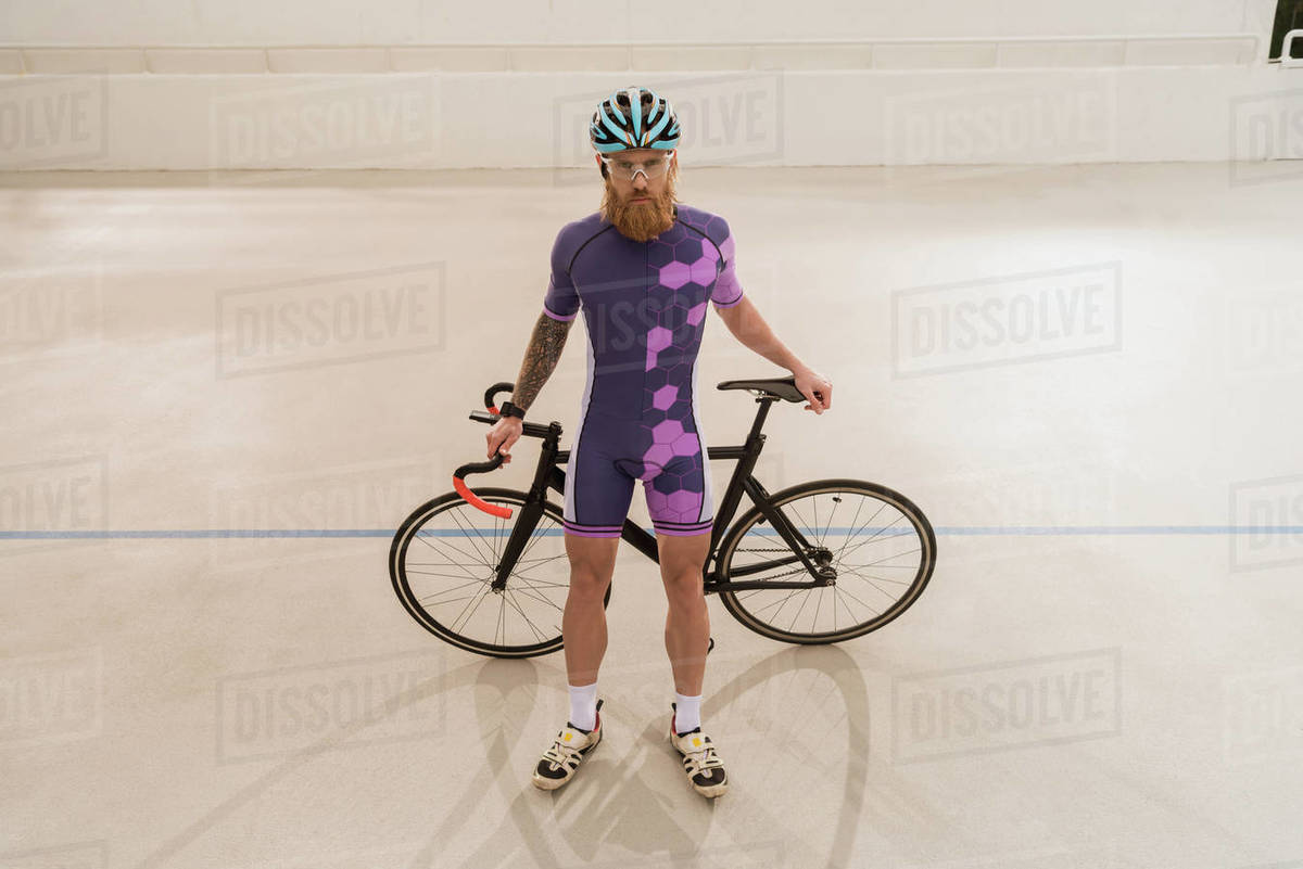 High angle view of cyclist in helmet leaning on bicycle and looking at ...