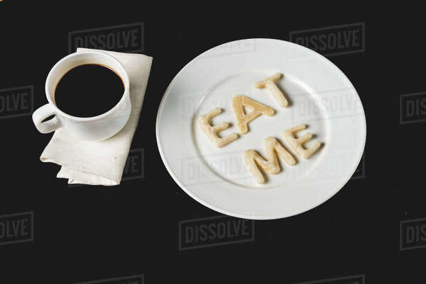 Top view of eat me lettering made from cookie dough on plate with ...