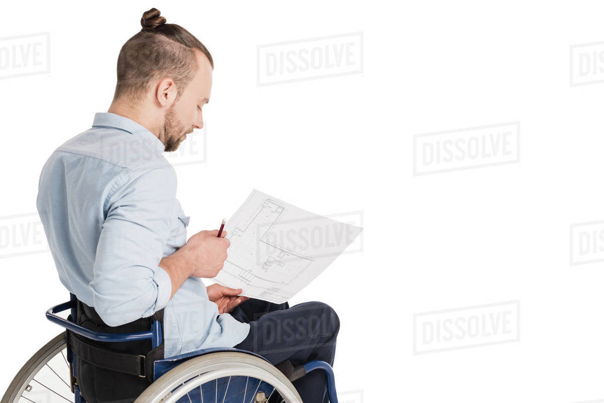 Young disabled architect in wheelchair working with blueprints ...