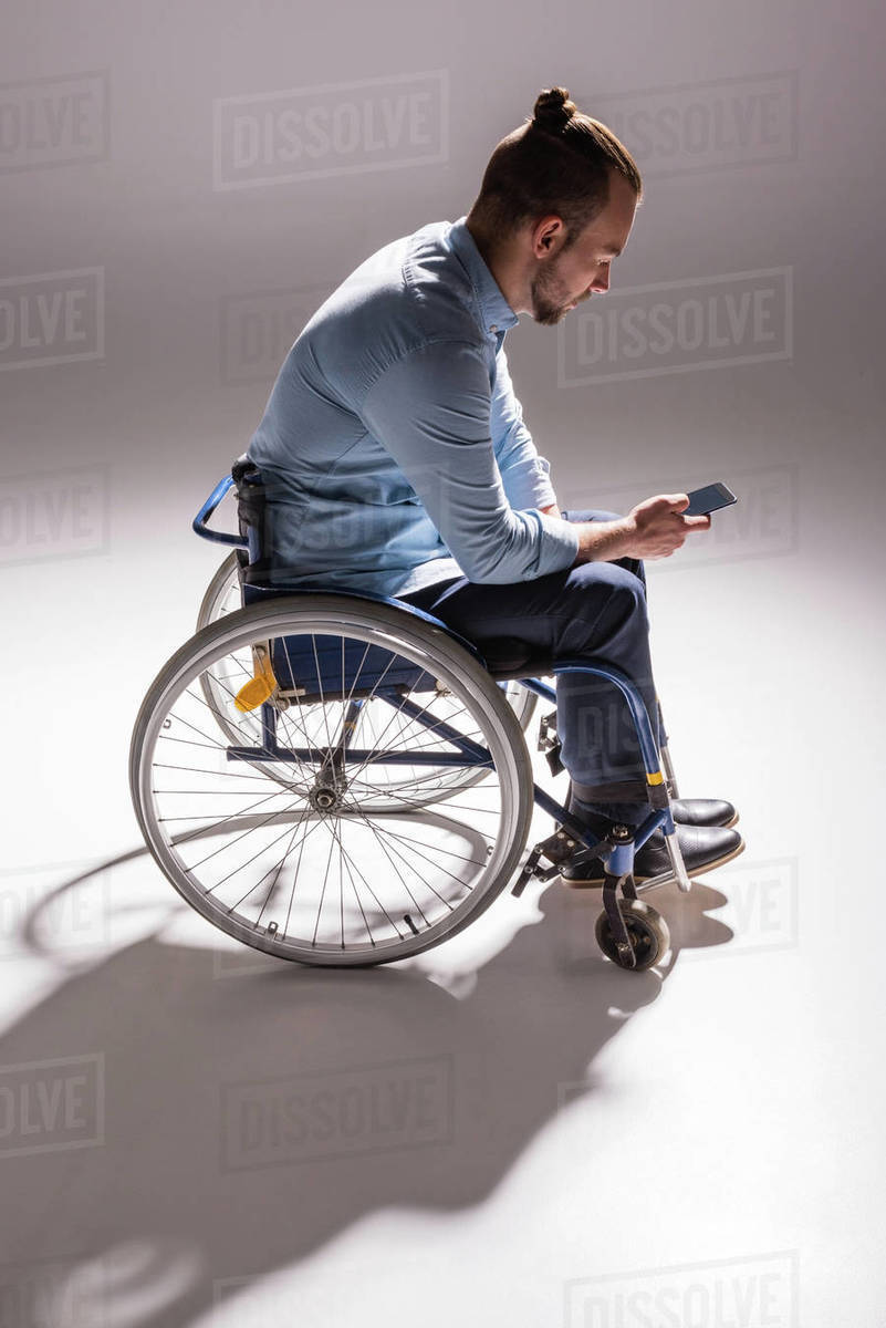 Side view shot of disabled man in wheelchair using smartphone - Royalty ...