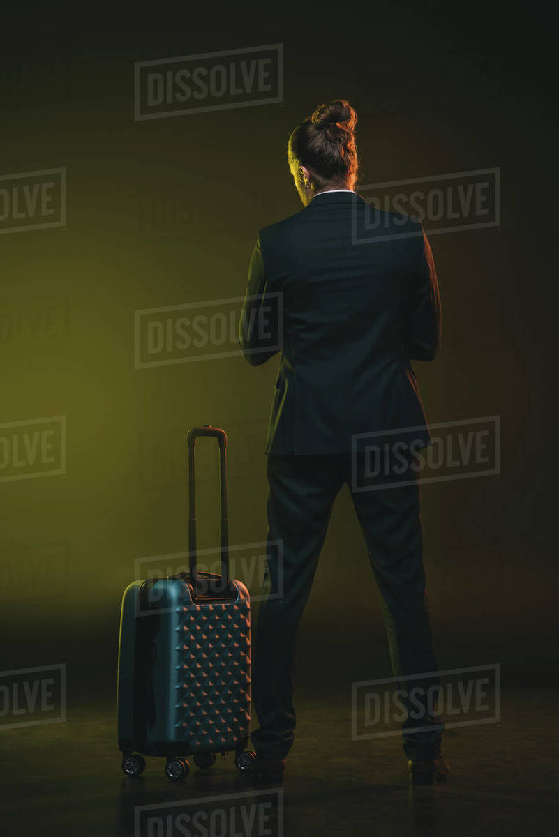 Back view of young man in suit standing near suitcase - Royalty-free ...