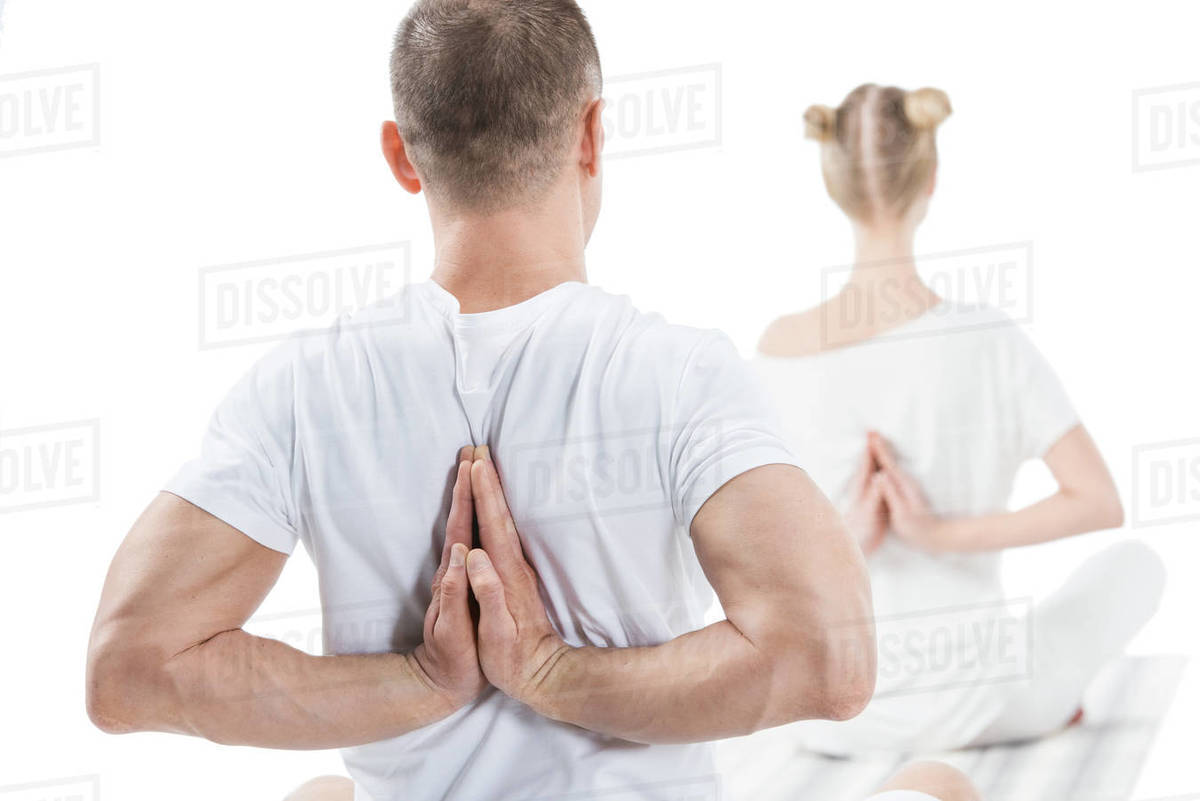 Back view of sporty young people sitting in lotus position with Namaste ...