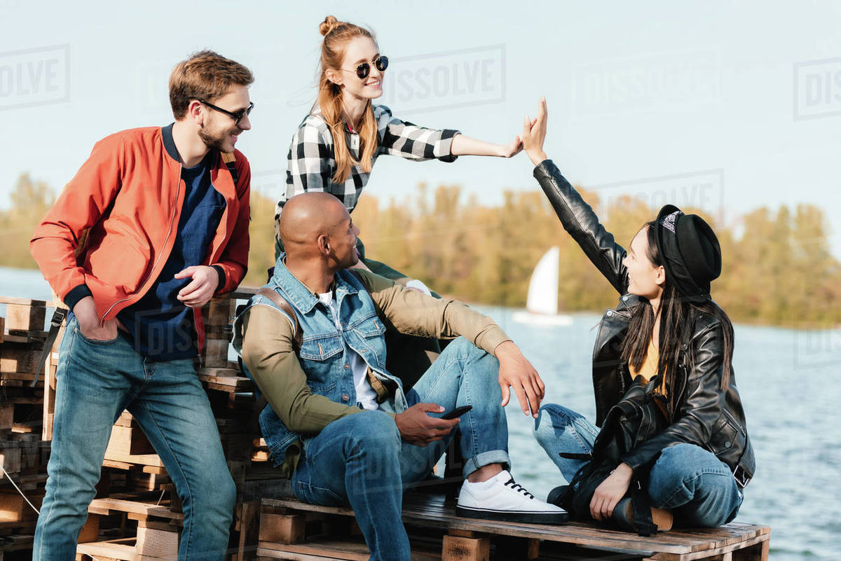 Multicultural women giving high five to each other while spending time ...