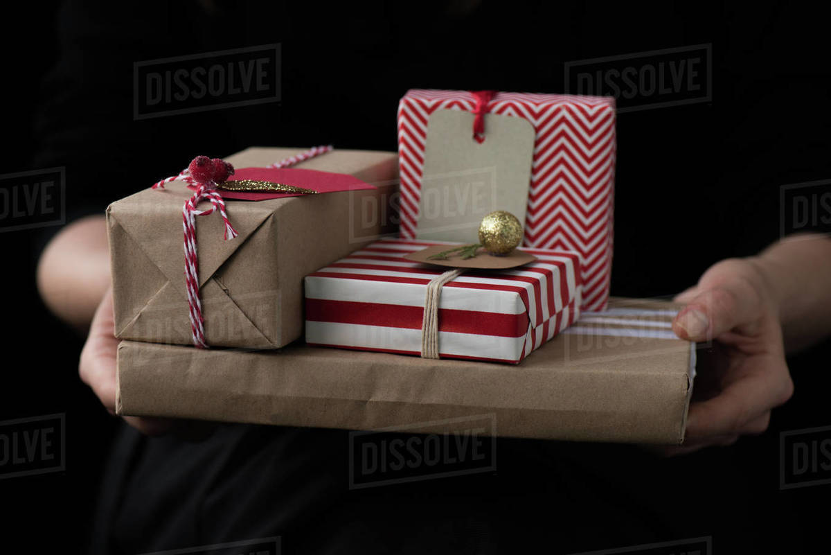 Cropped shot of woman holding wrapped christmas gifts in hands isolated ...