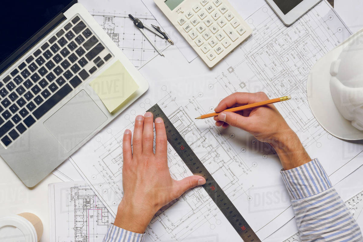 partial view of architect working with blueprints on new building ...