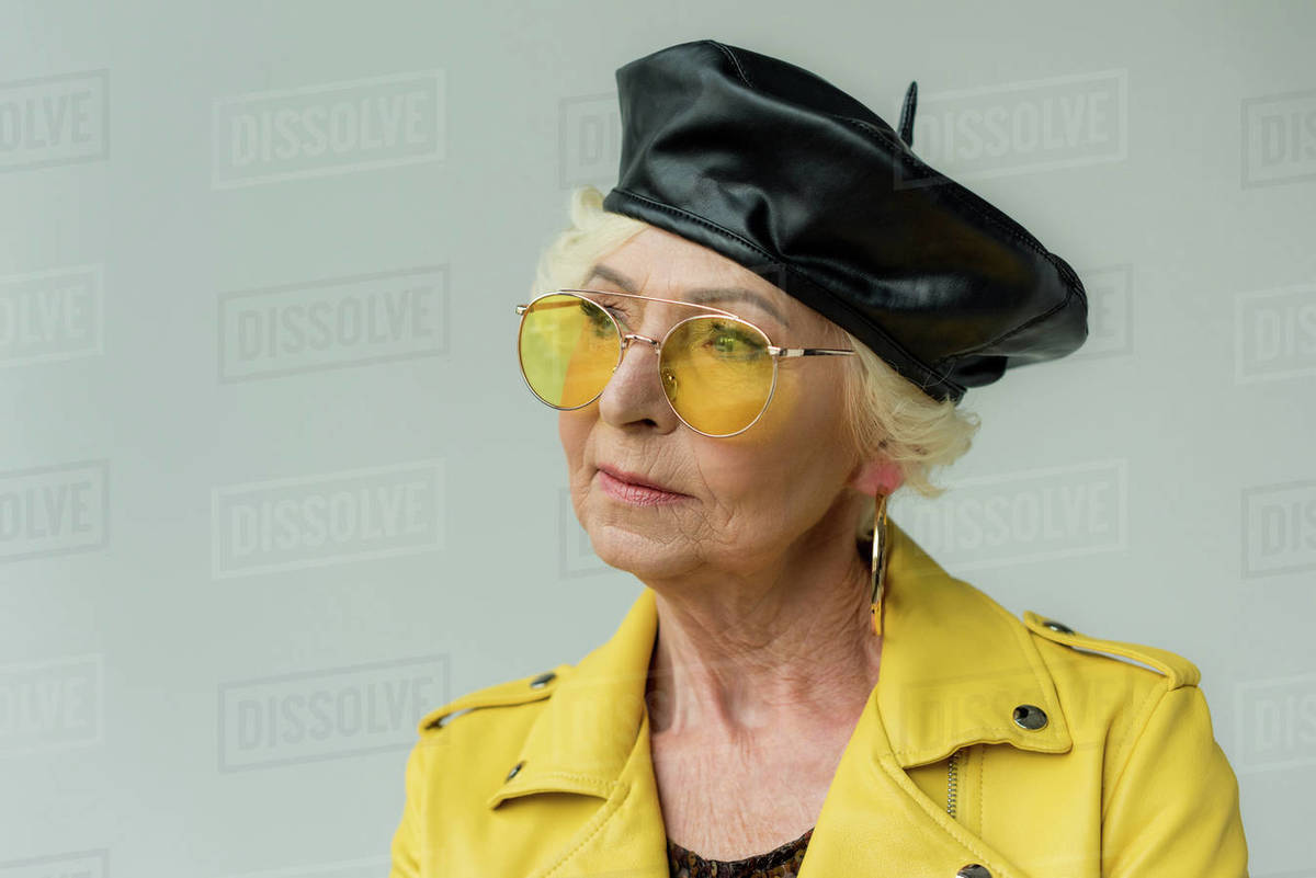 fashionable senior woman in yellow leather jacket, beret and yellow ...
