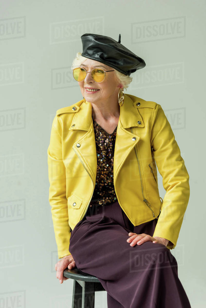 stylish senior woman in yellow jacket and leather beret, isolated on ...