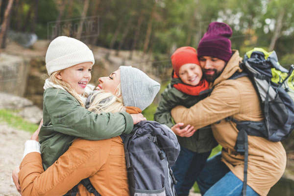 Side view of parents hugging little children in autumn forest - Royalty ...