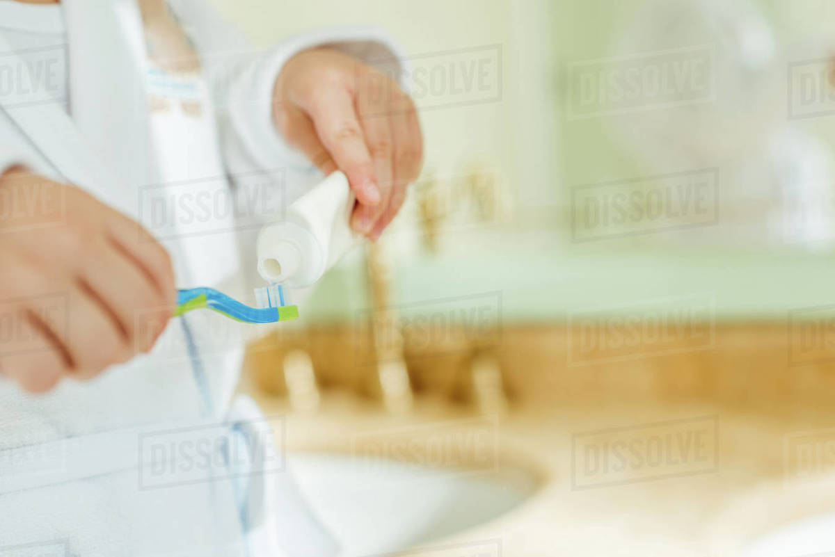 Close-up partial view of child holding toothpaste and toothbrush ...