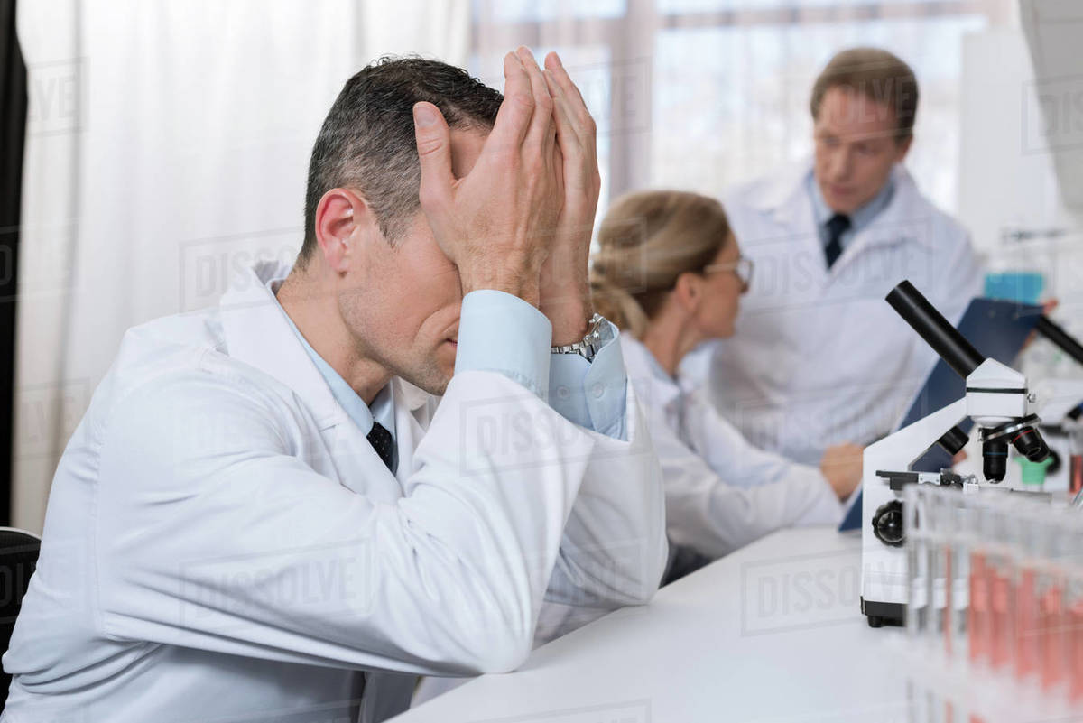Tired scientist during work at modern biological laboratory covering ...
