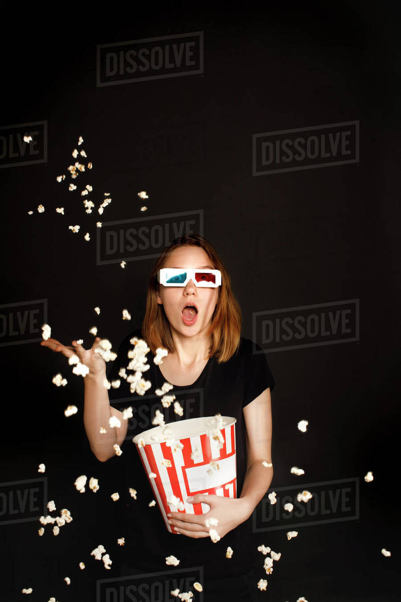 Shocked woman with bucket of popcorn isolated on black - Royalty-free ...