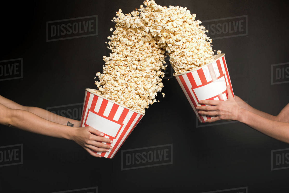 Cropped shot of people with buckets of popcorn isolated on black ...