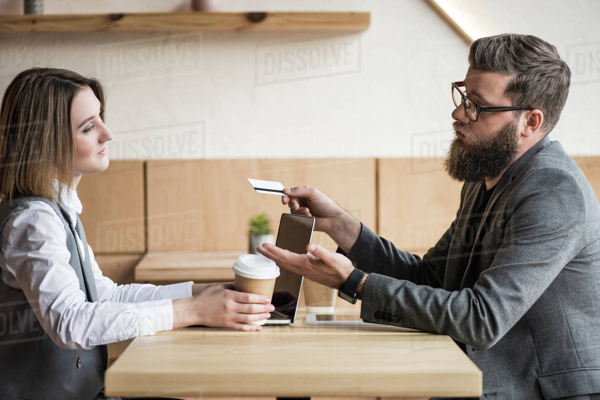 Businessman giving credit card to female partner - Stock Photo - Dissolve