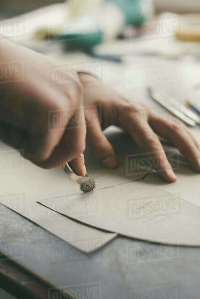 Cropped shot of craftsman tracing leather sheets to create shoes ...