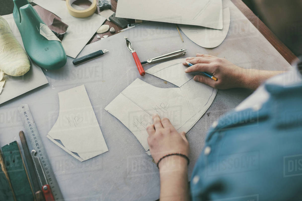 Cropped shot of middle aged shoemaker tracing leather for shoes at ...
