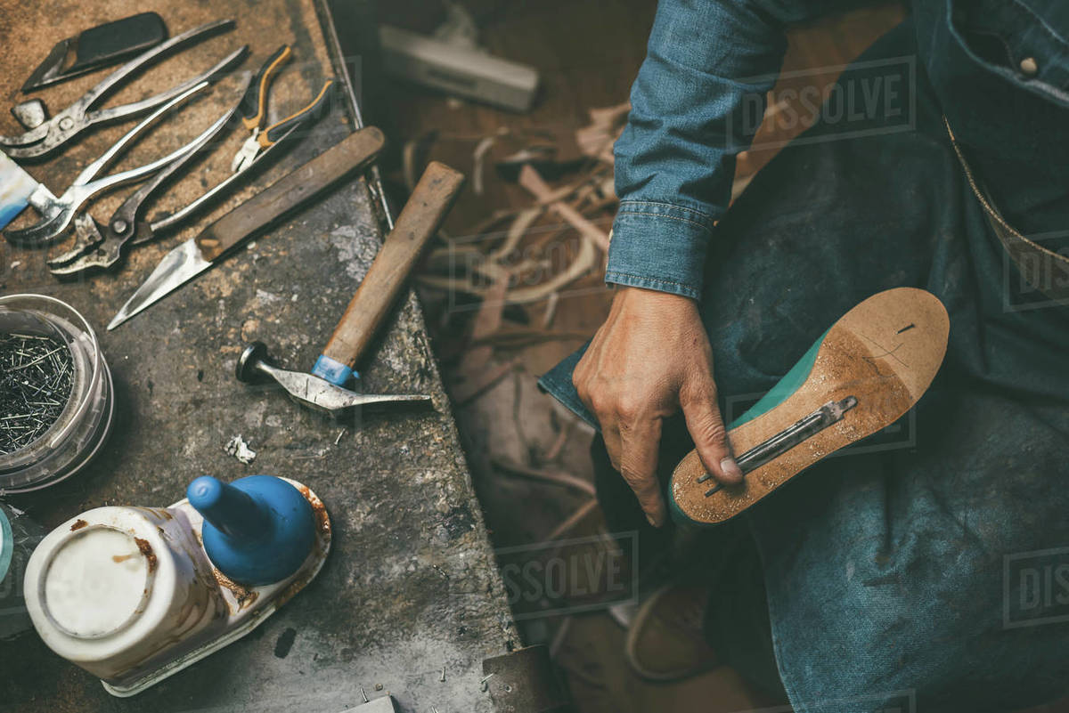 Cropped shot of shoemaker holding plastic boot workpiece and working ...