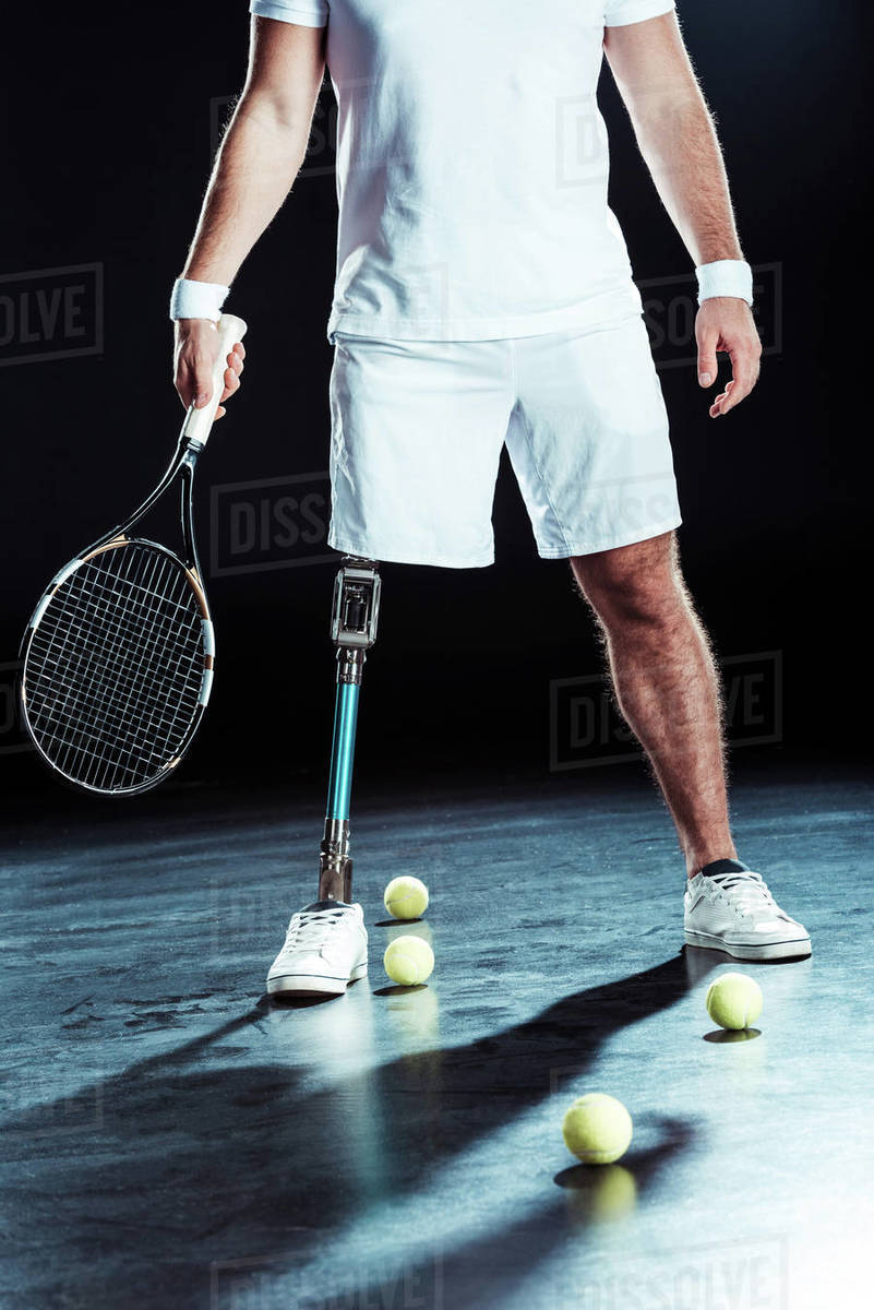 Cropped shot of tennis player holding tennis racket with tennis balls ...