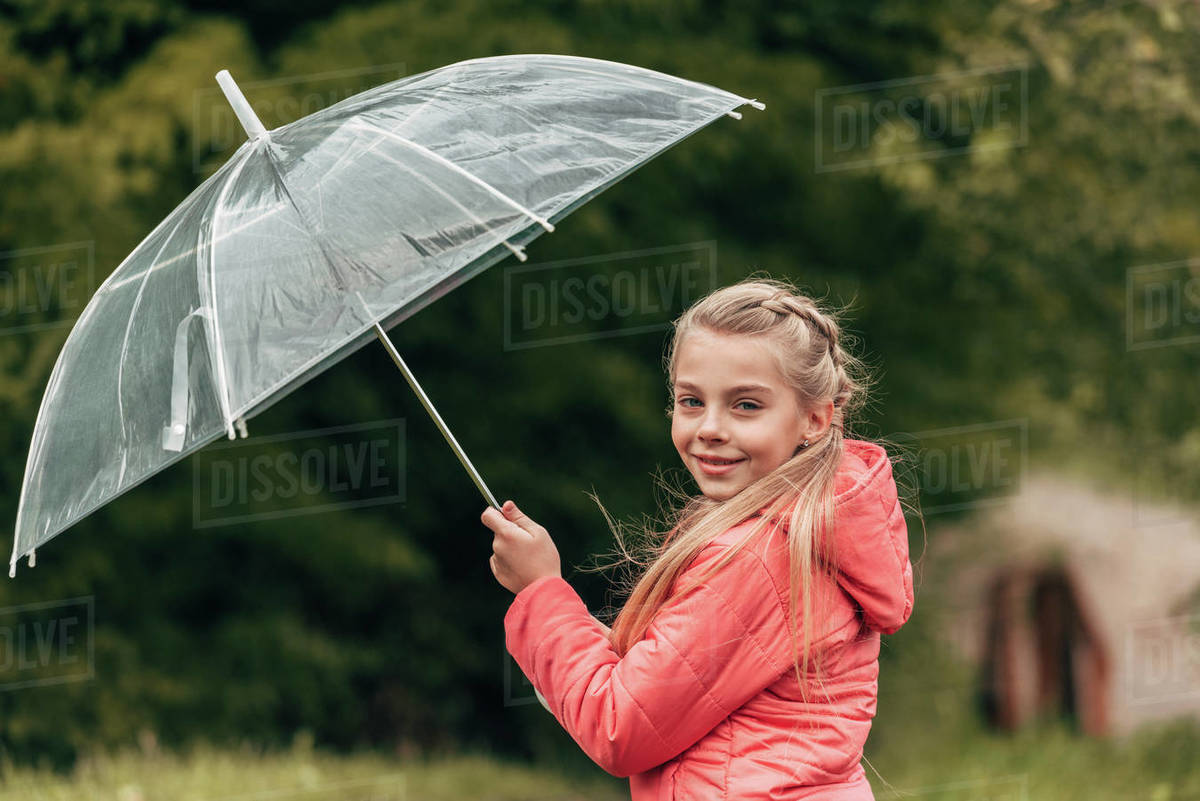 adorable little child holding umbrella and smiling at camera in autumn ...