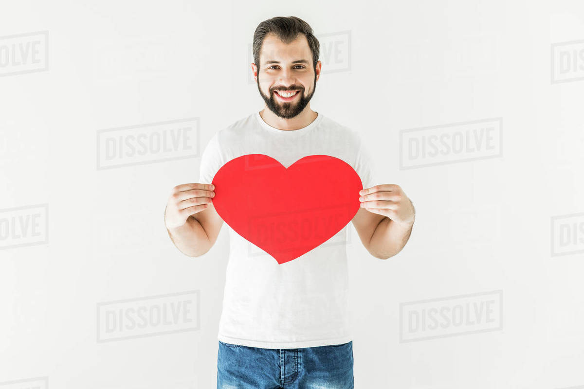 Handsome bearded man holding red heart symbol and smiling at camera ...