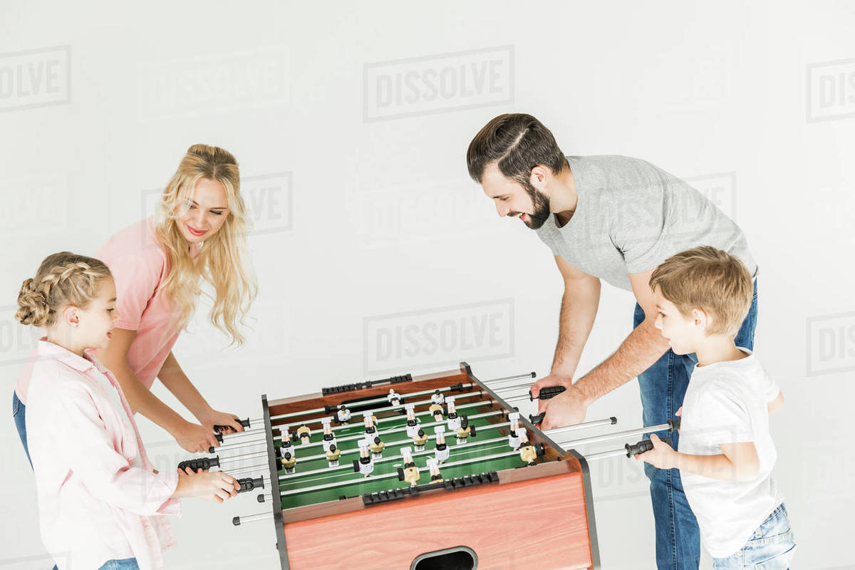 Happy family with two kids playing table football together isolated on ...