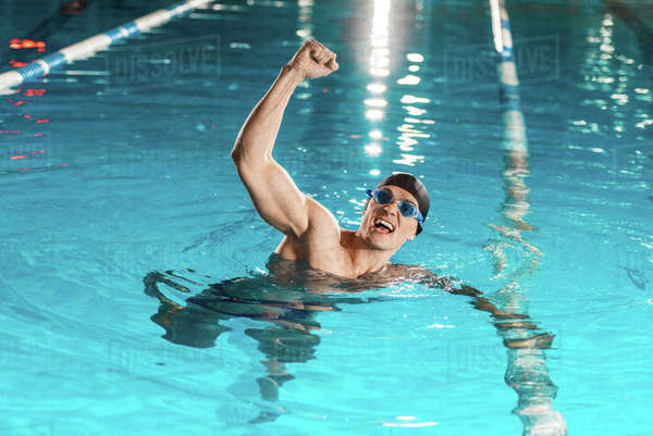 Handsome winning muscular swimmer in competition swimming pool ...