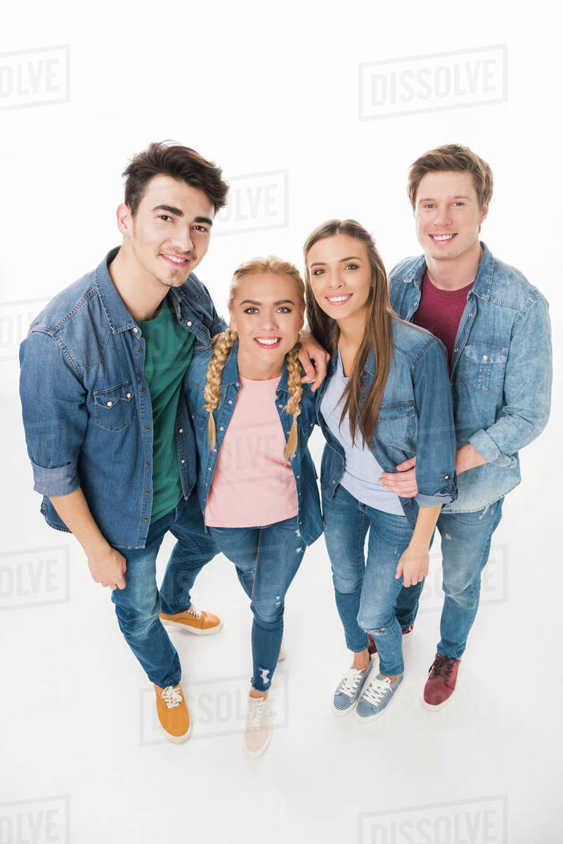 Happy young friends standing together and smiling at camera isolated on ...