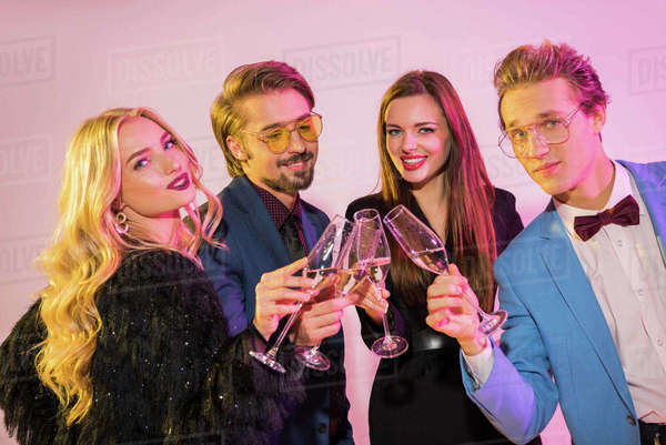 Happy glamorous friends clinking with champagne glasses having fun on ...
