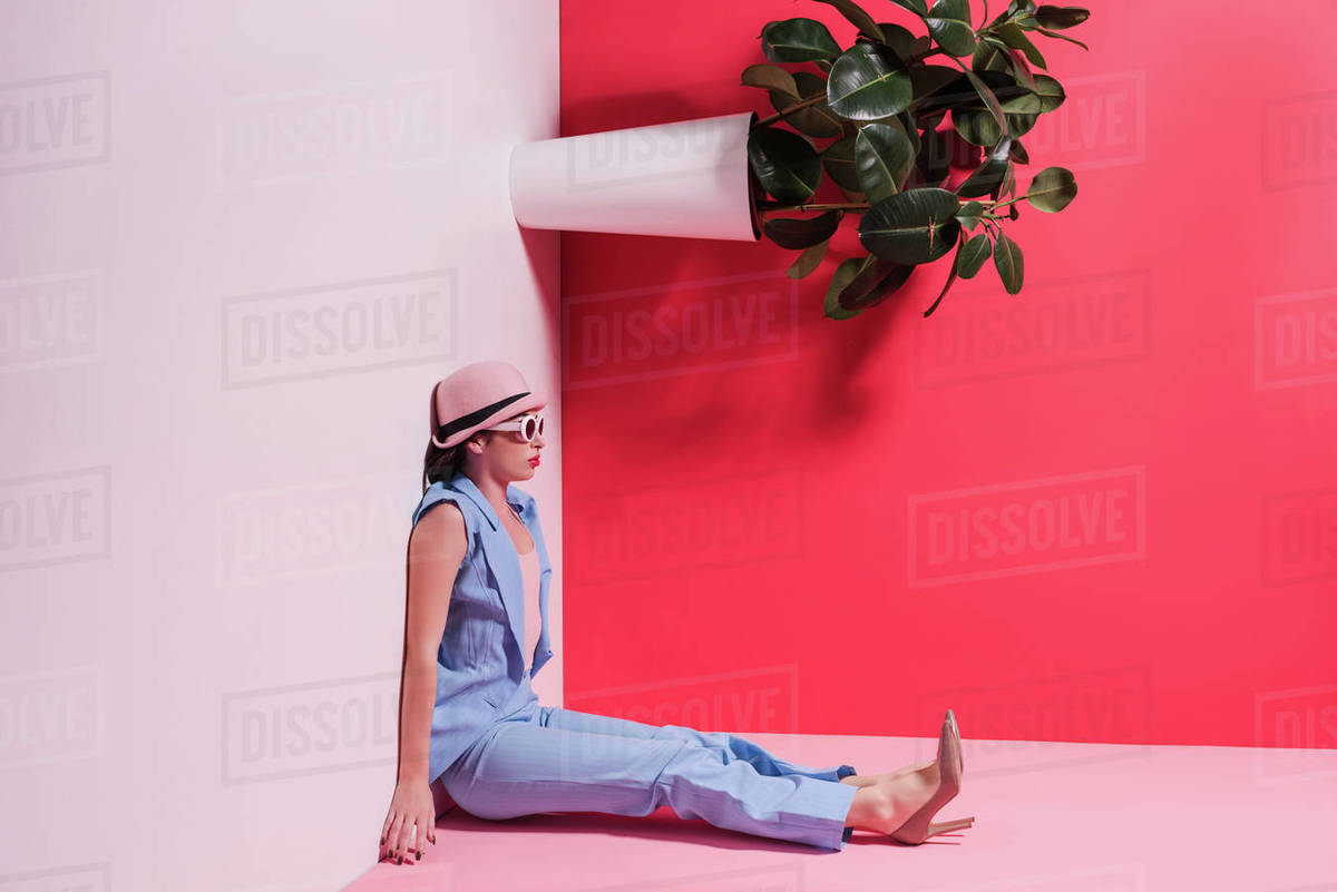Side view of stylish girl in hat and sunglasses sitting upside down in ...