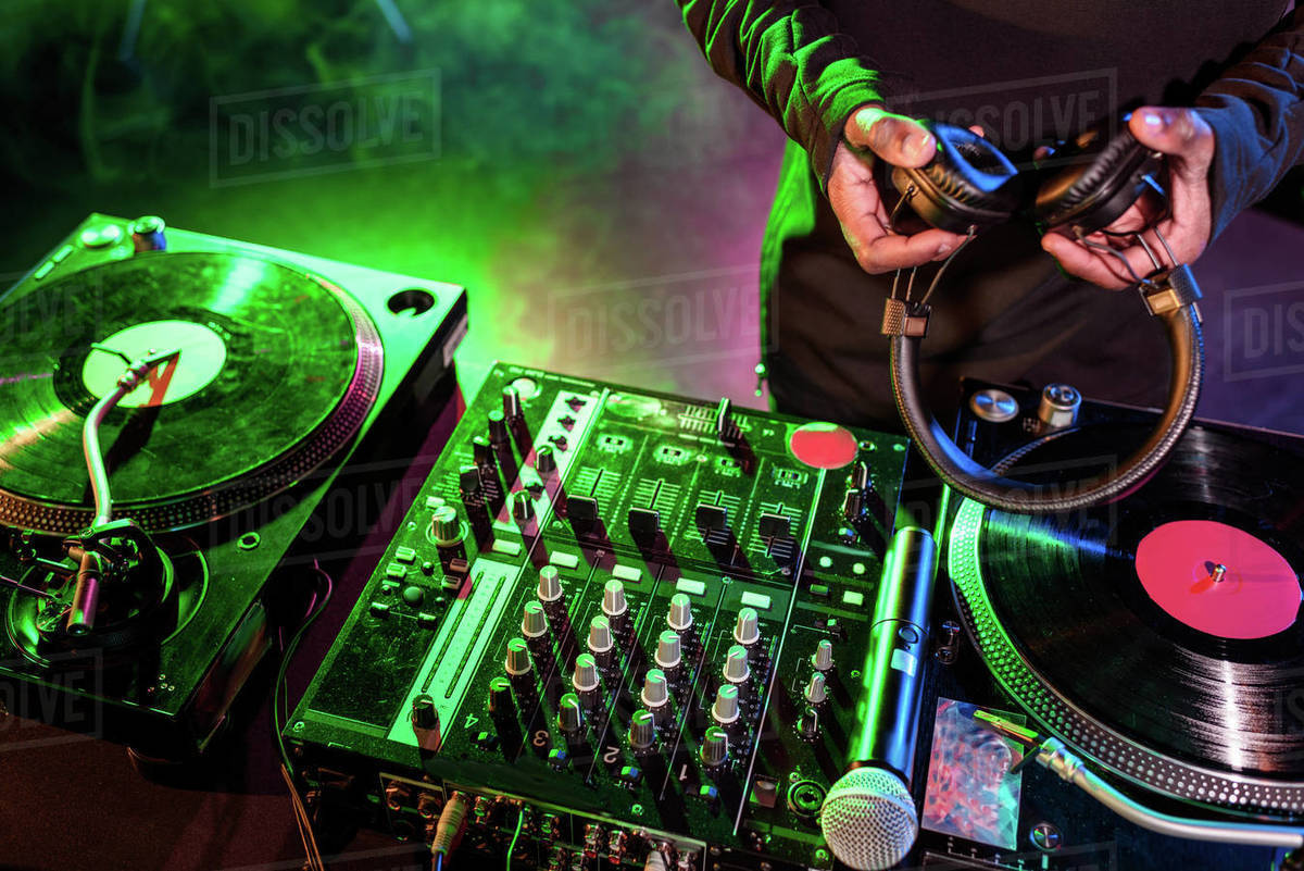 Cropped view of club dj hands holding headphones over sound mixer ...