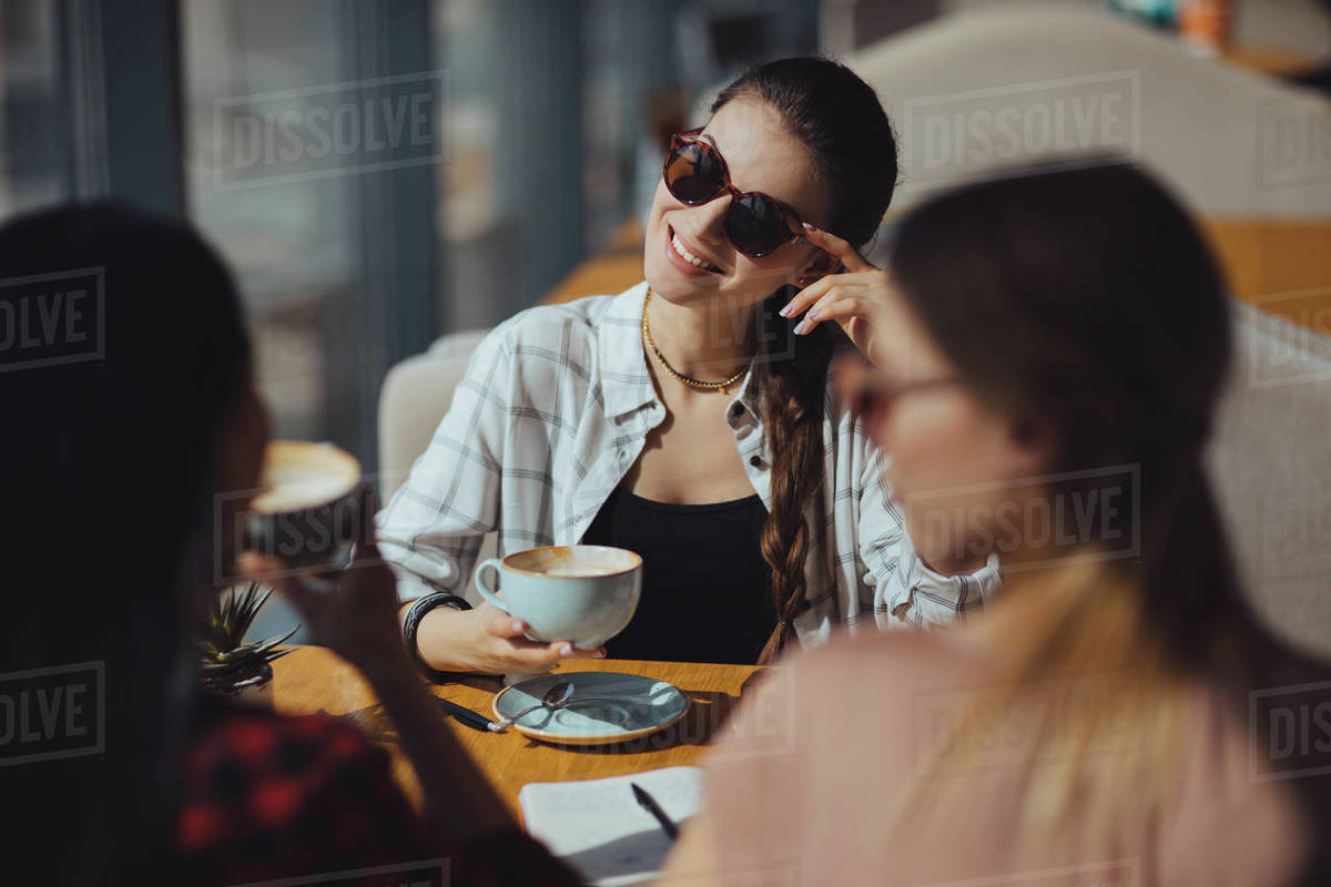 Young attractive multicultural women on coffee break in cafe - Royalty ...