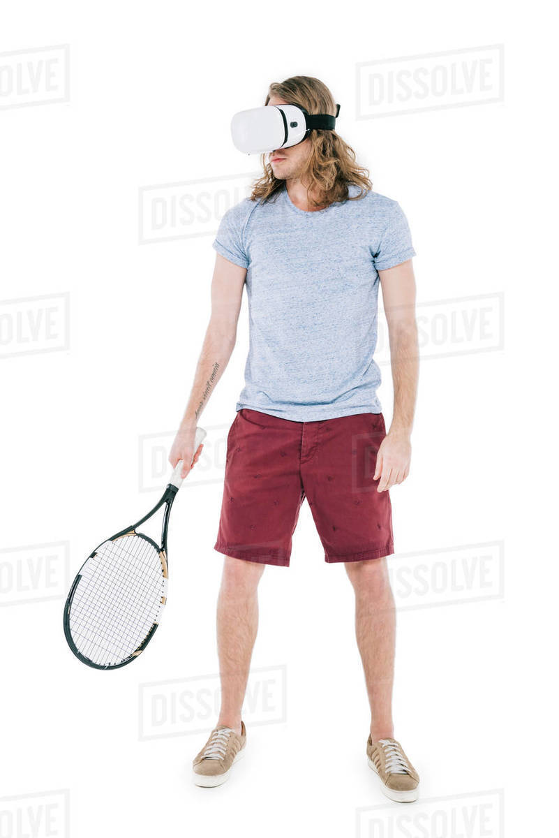 Handsome young man in virtual reality headset holding tennis racquet ...