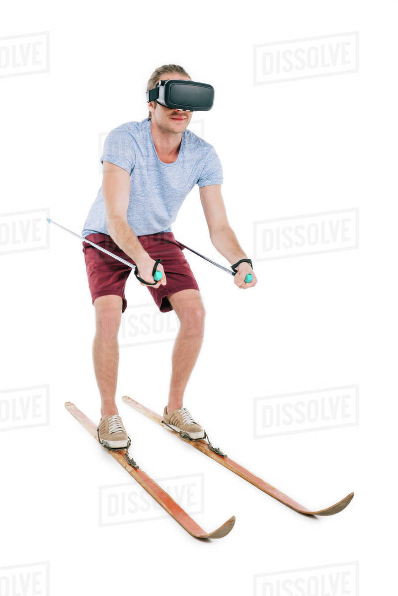Full length view of young man in virtual reality headset skiing ...