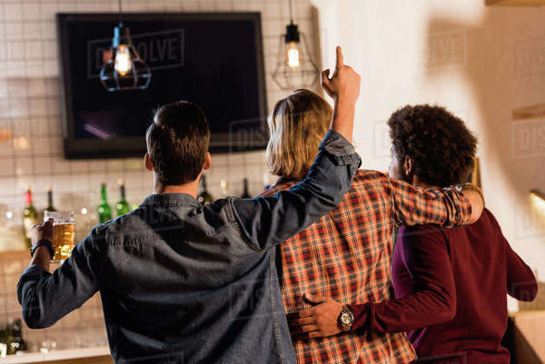 Back view of young friends with beer watching tv in bar - Royalty-free ...