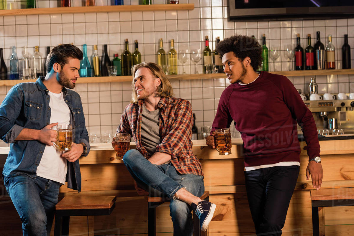 Smiling young men drinking beer together in bar - Royalty-free Stock ...