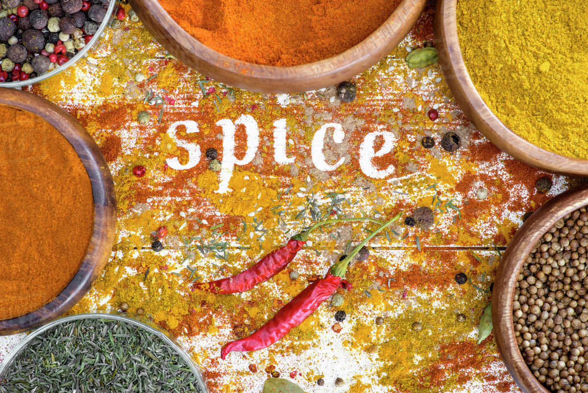 Top view on scattered spices on table with wooden bowls and word spice ...