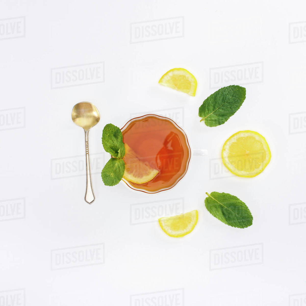 Top view of tea in glass, spoon, lemon slices and peppermint on grey ...
