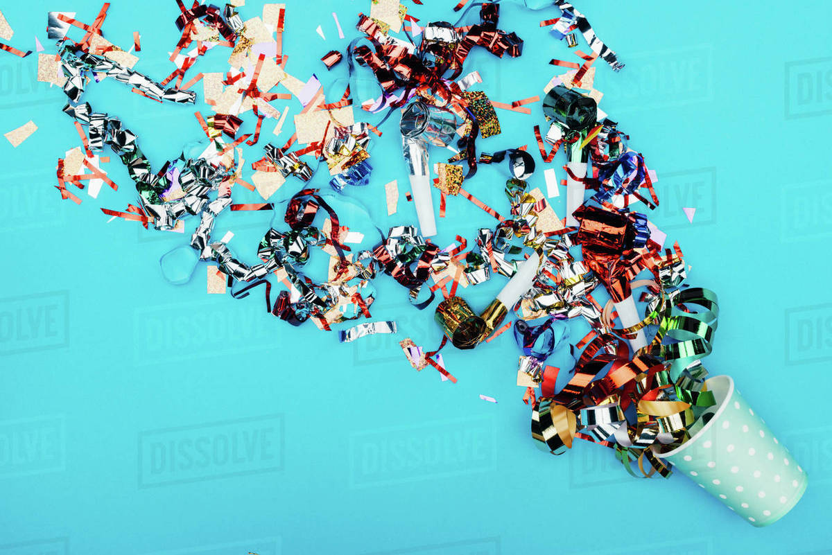 Top view of confetti spilled from paper cup on blue surface - Royalty ...